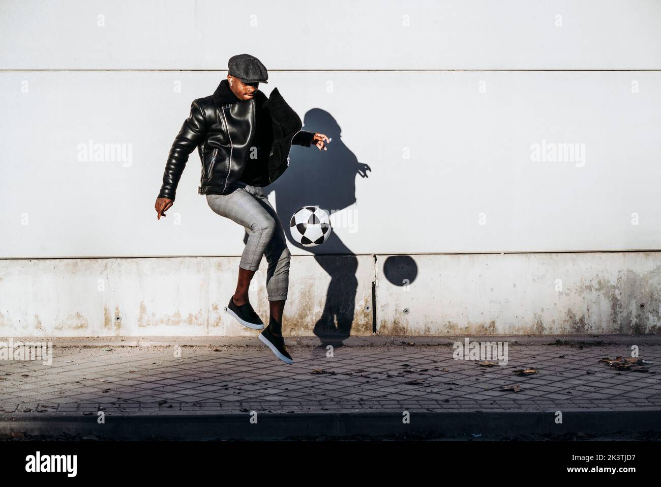 Black man kicking ball on street Stock Photo - Alamy