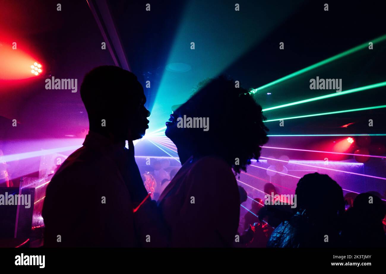 Silhouettes of happy black couple dancing against colorful neon ...