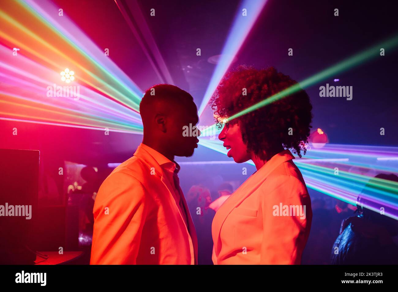 Happy black couple dancing against colorful neon illumination during ...