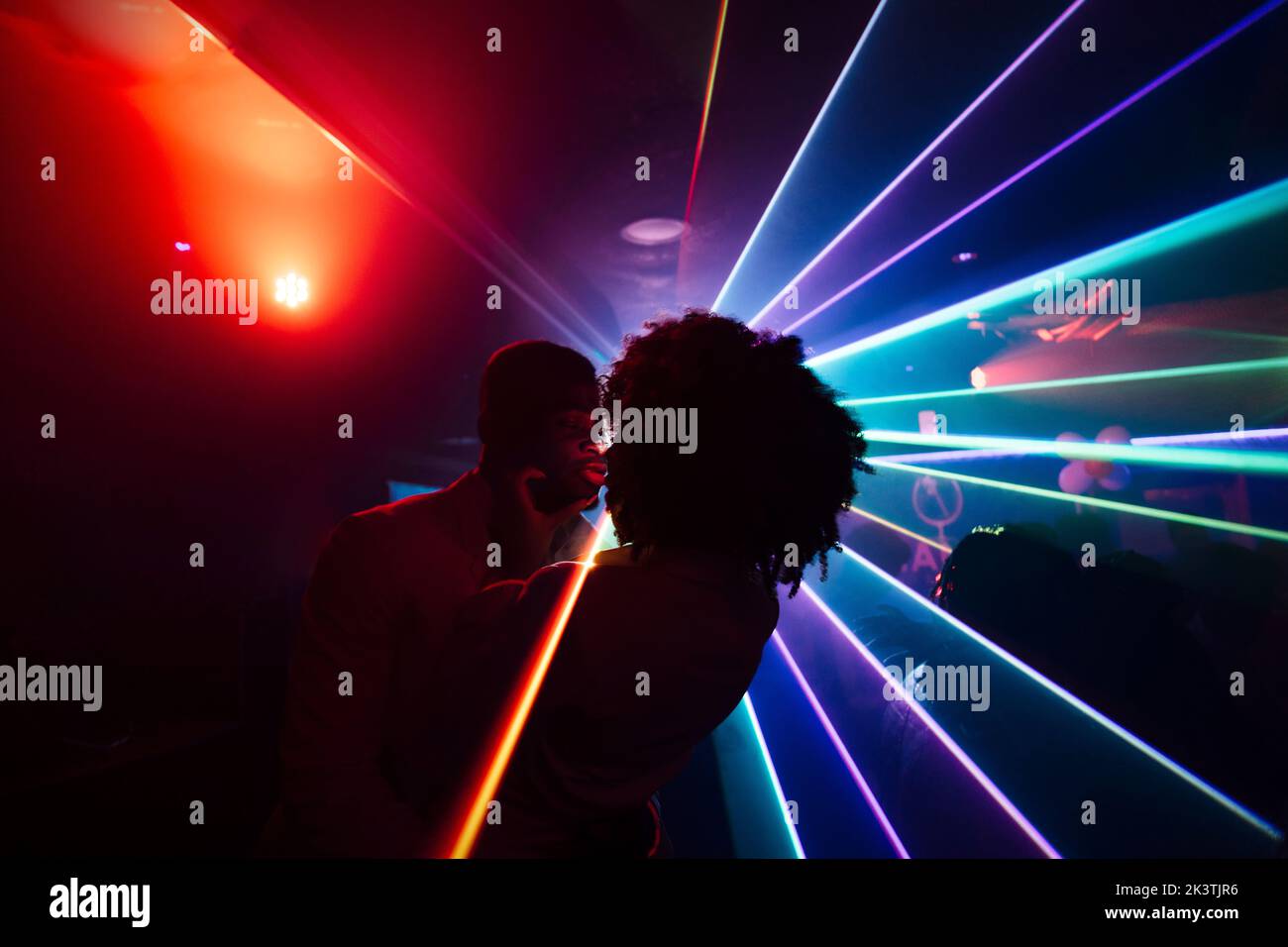 Happy black couple dancing against colorful neon illumination during ...