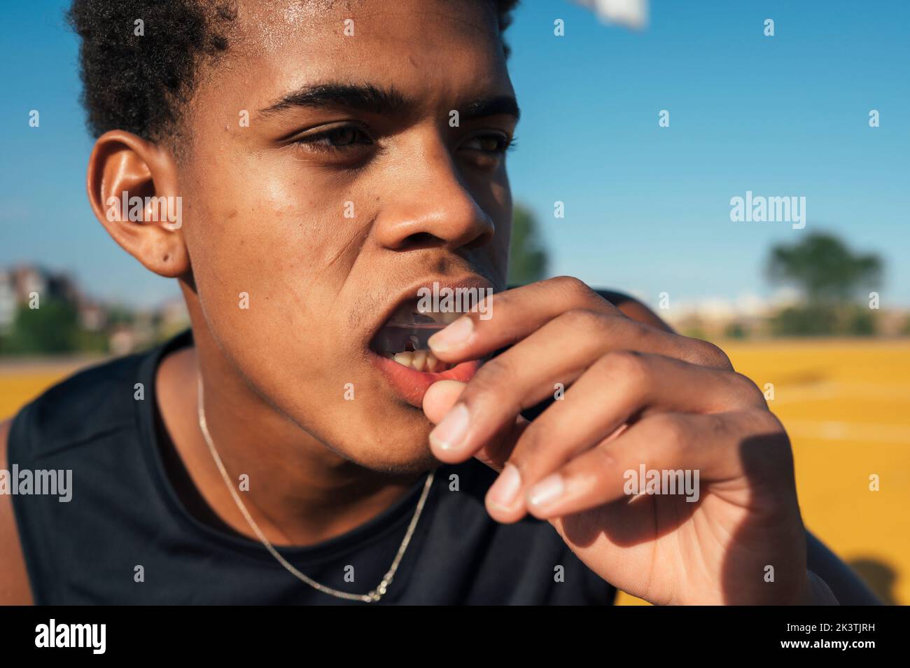 Young African American sportsman with split tooth placing transparent ...