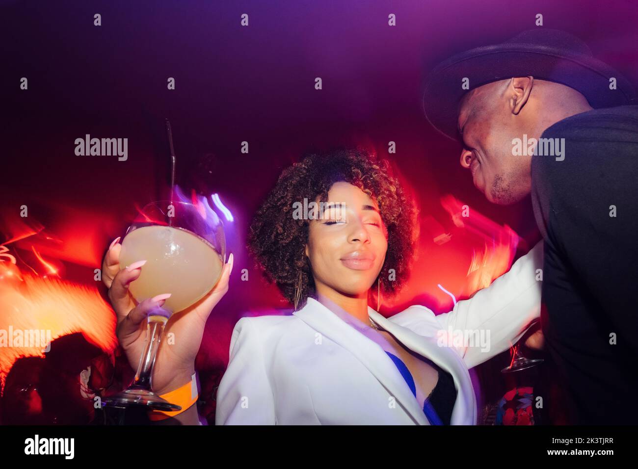 Drunk African American couple dancing under bright neon light while ...