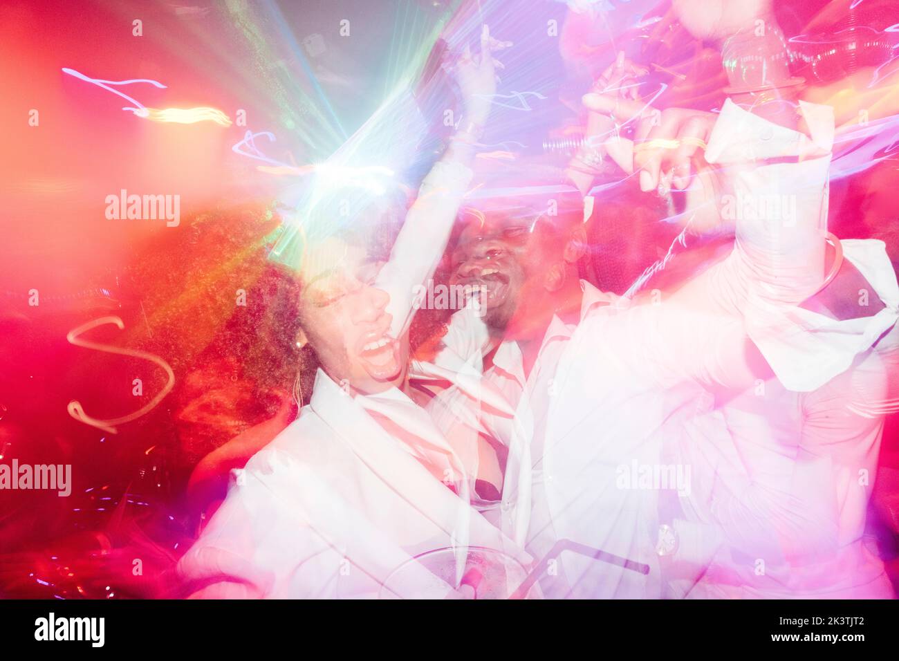 Drunk African American couple screaming and dancing under bright neon ...