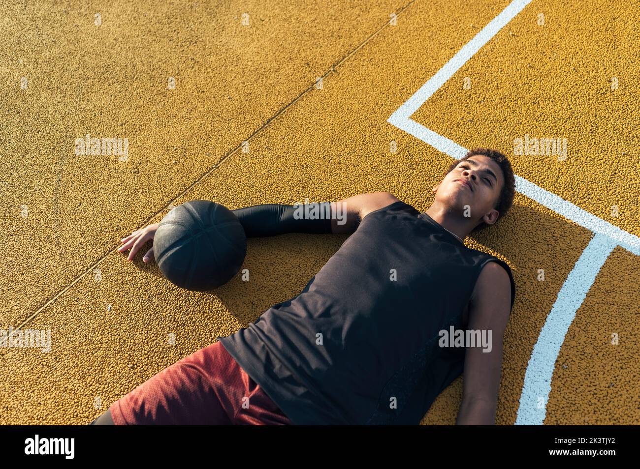 Tired African American sportsman in uniform having rest lying down on ...