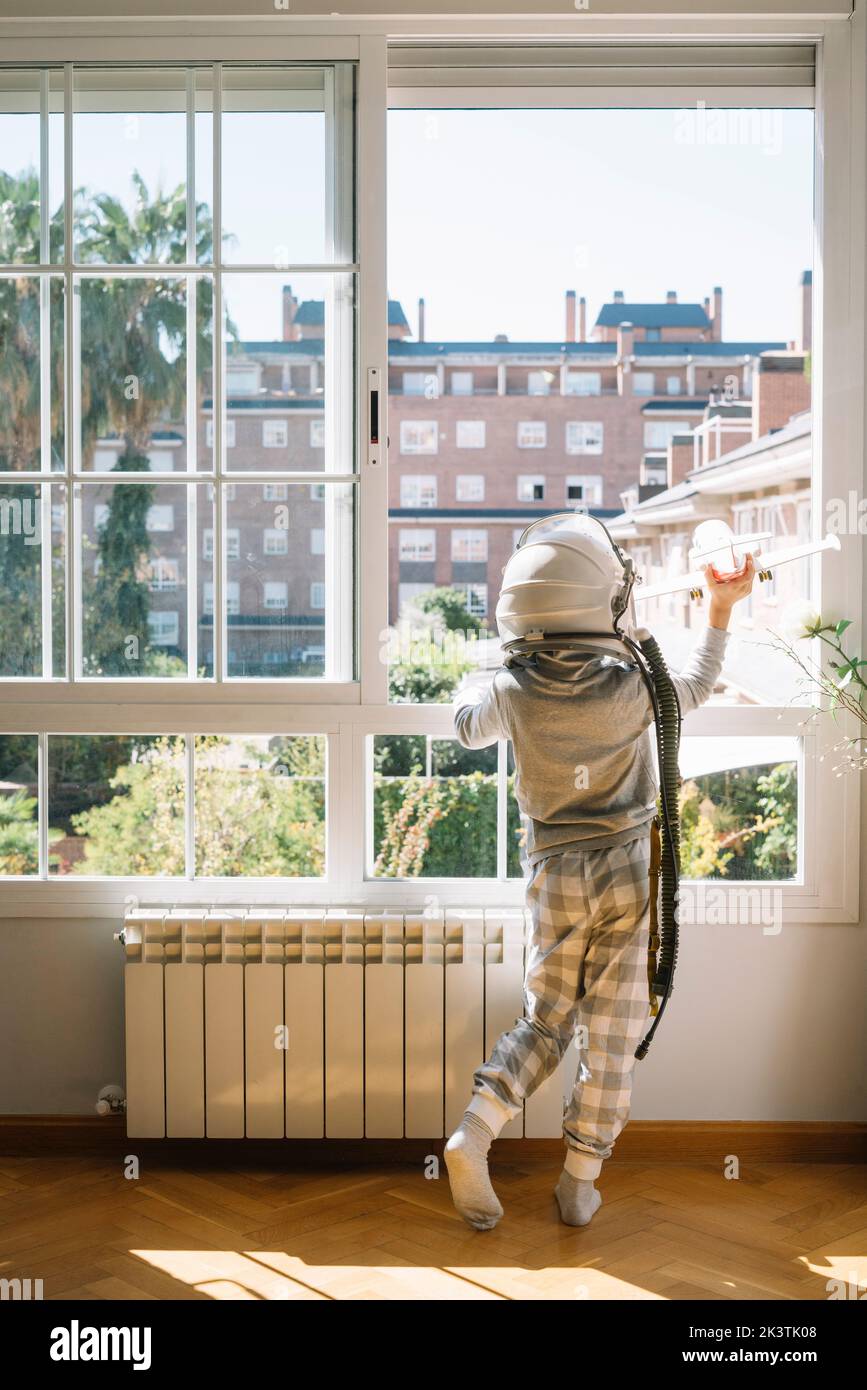 Adorable kid wearing a helmet and playing alone with a space shuttle at ...