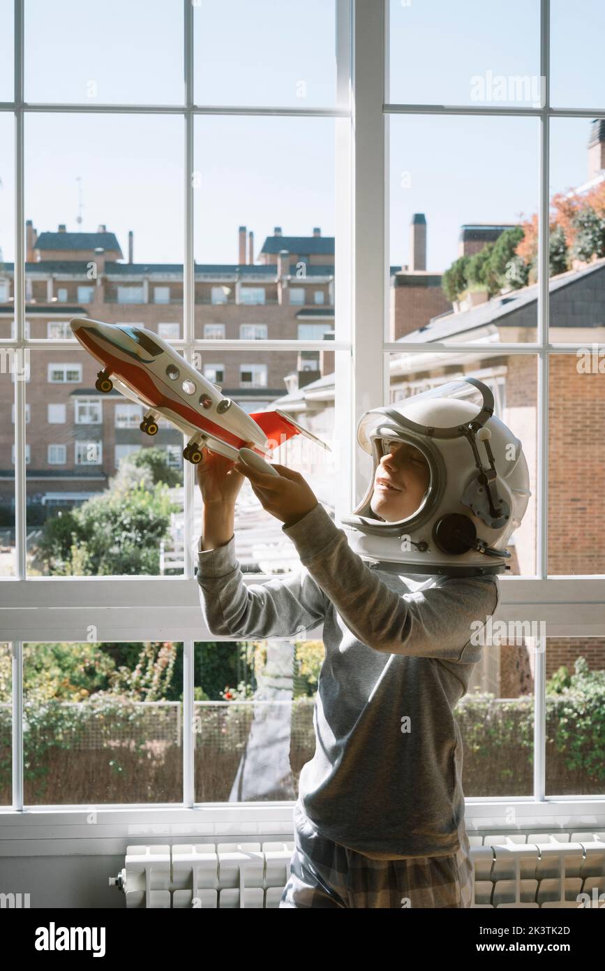 Adorable kid with astronaut helmet. He is playing alone with a space ...