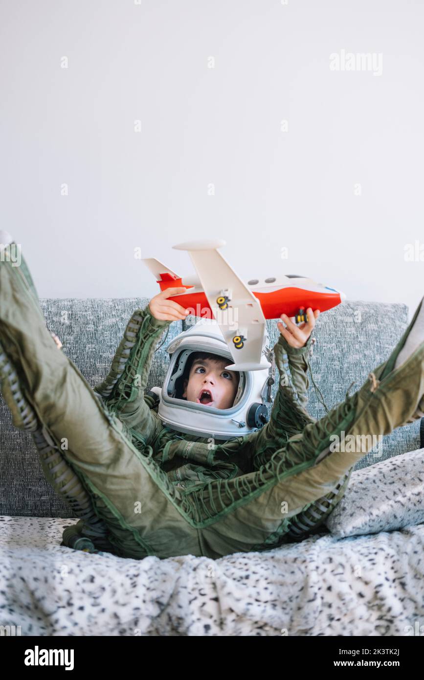 Adorable kid with a real astronaut uniform. He is playing alone with a ...