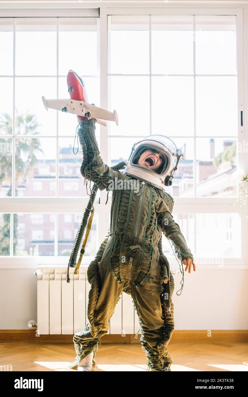 Adorable kid with a real astronaut uniform. He is playing alone with a ...