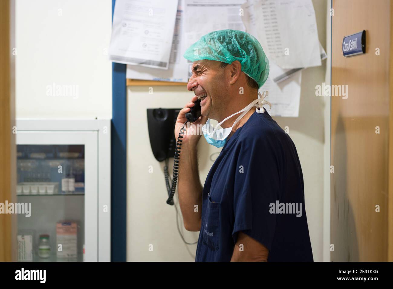 Side view of adult man in surgeon uniform laughing while talking on ...