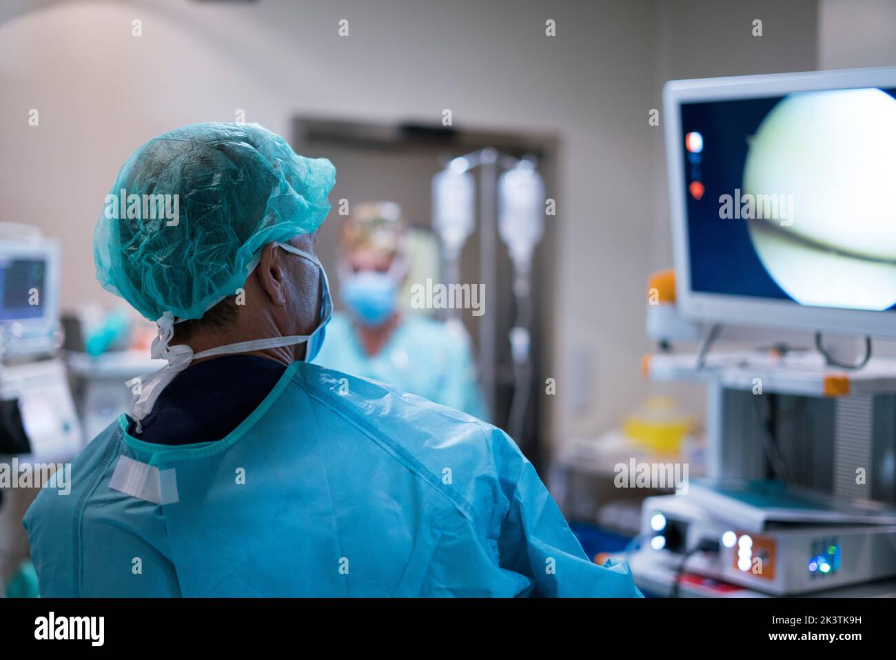 Back view of man in surgeon uniform looking at monitor while performing ...