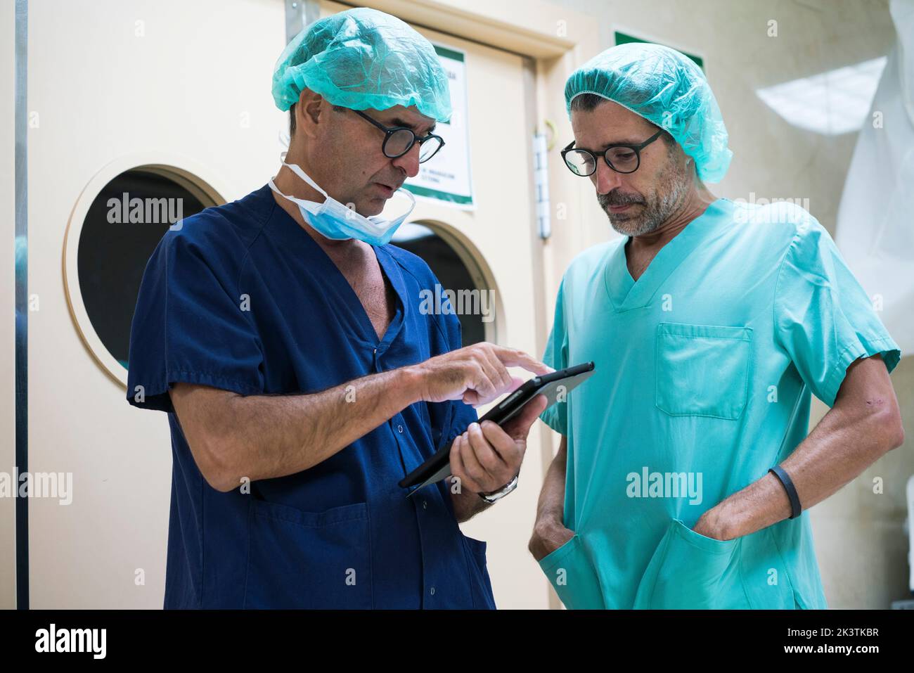 Two men in surgeon uniform standing in hospital corridor and using ...
