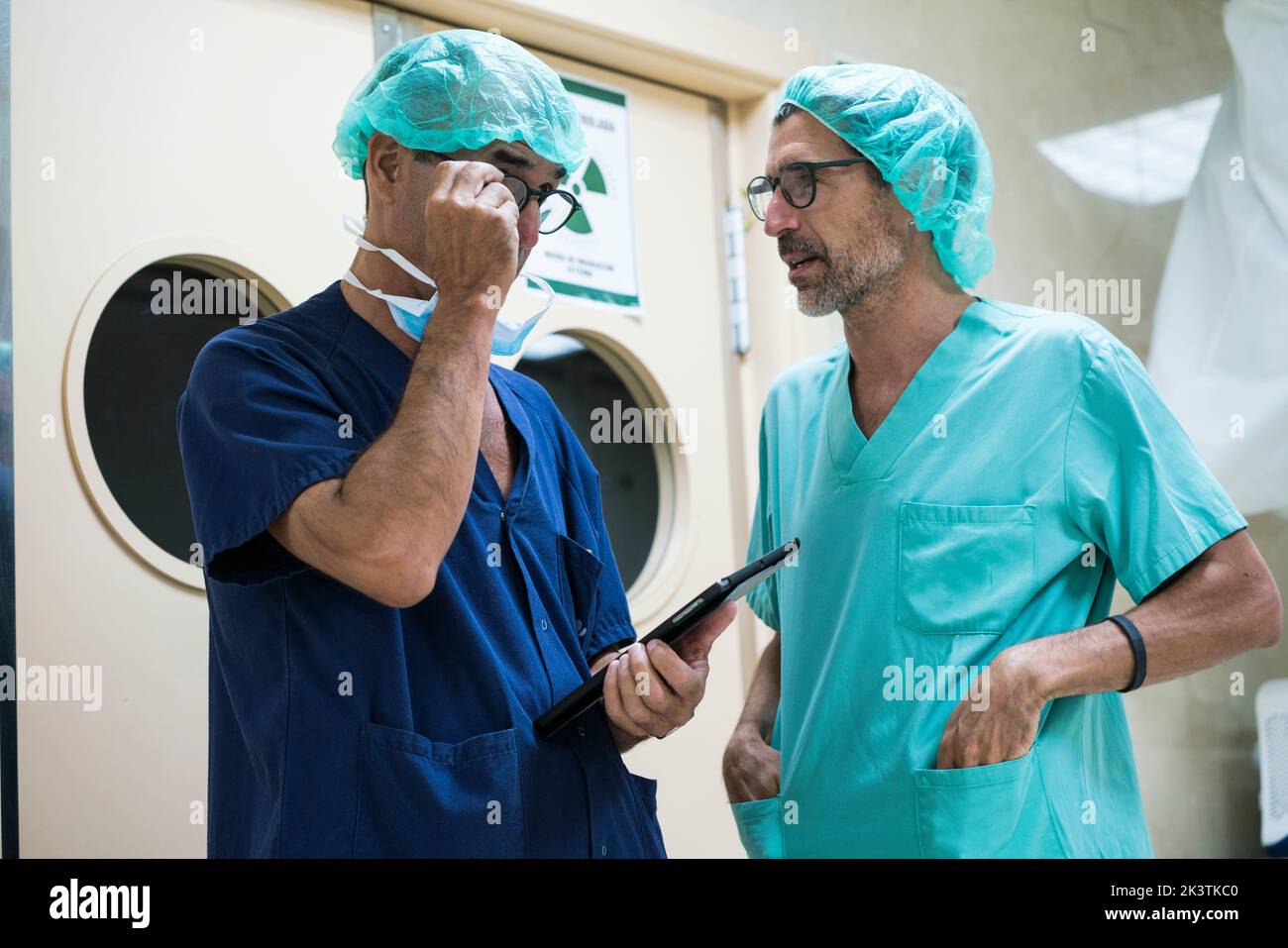 Two men in surgeon uniform standing in hospital corridor and using ...