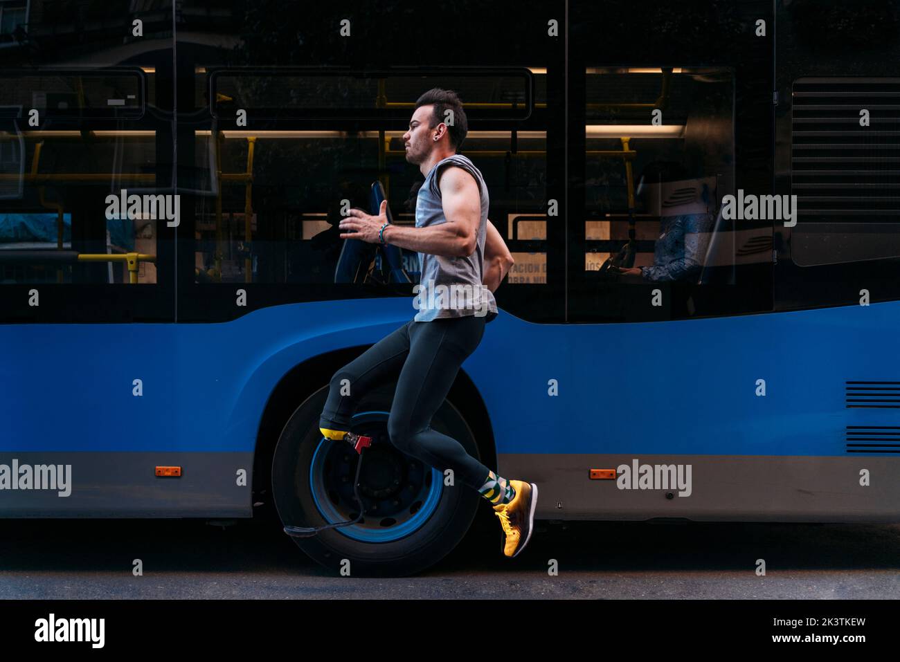 Side view of strong male with leg prosthesis running fast on street ...