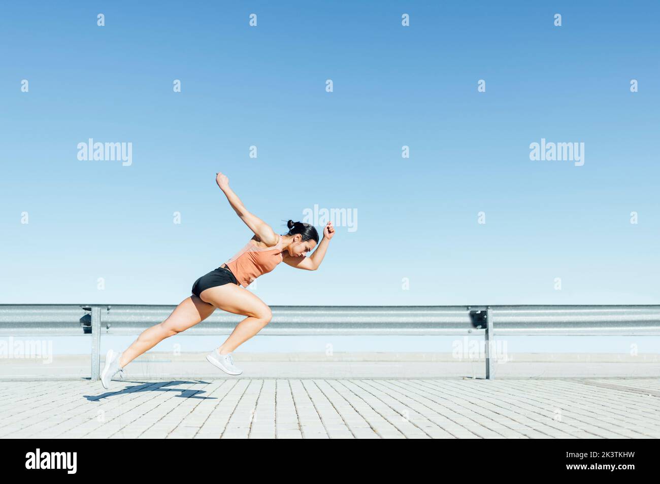 Phases of side view female athlete starting race and running fast on ...