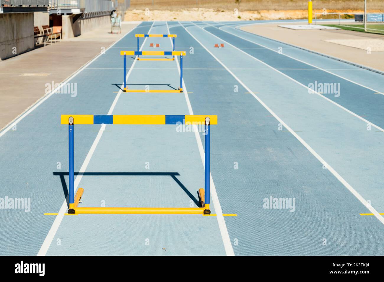 Row of colorful hurdles placed on blue racetrack during track and field ...