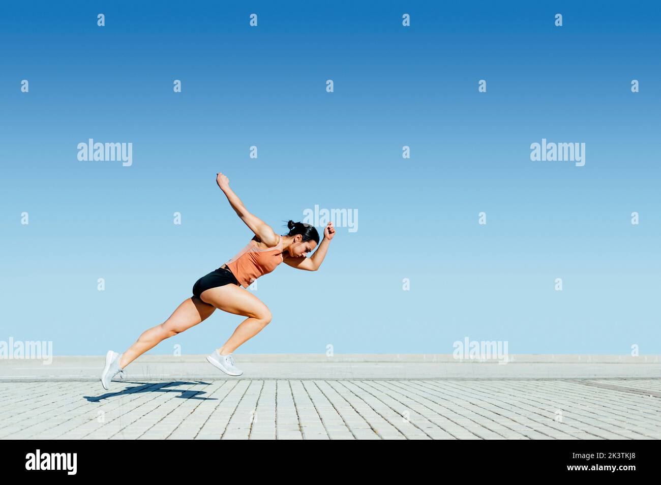 Phases of side view female athlete starting race and running fast on ...