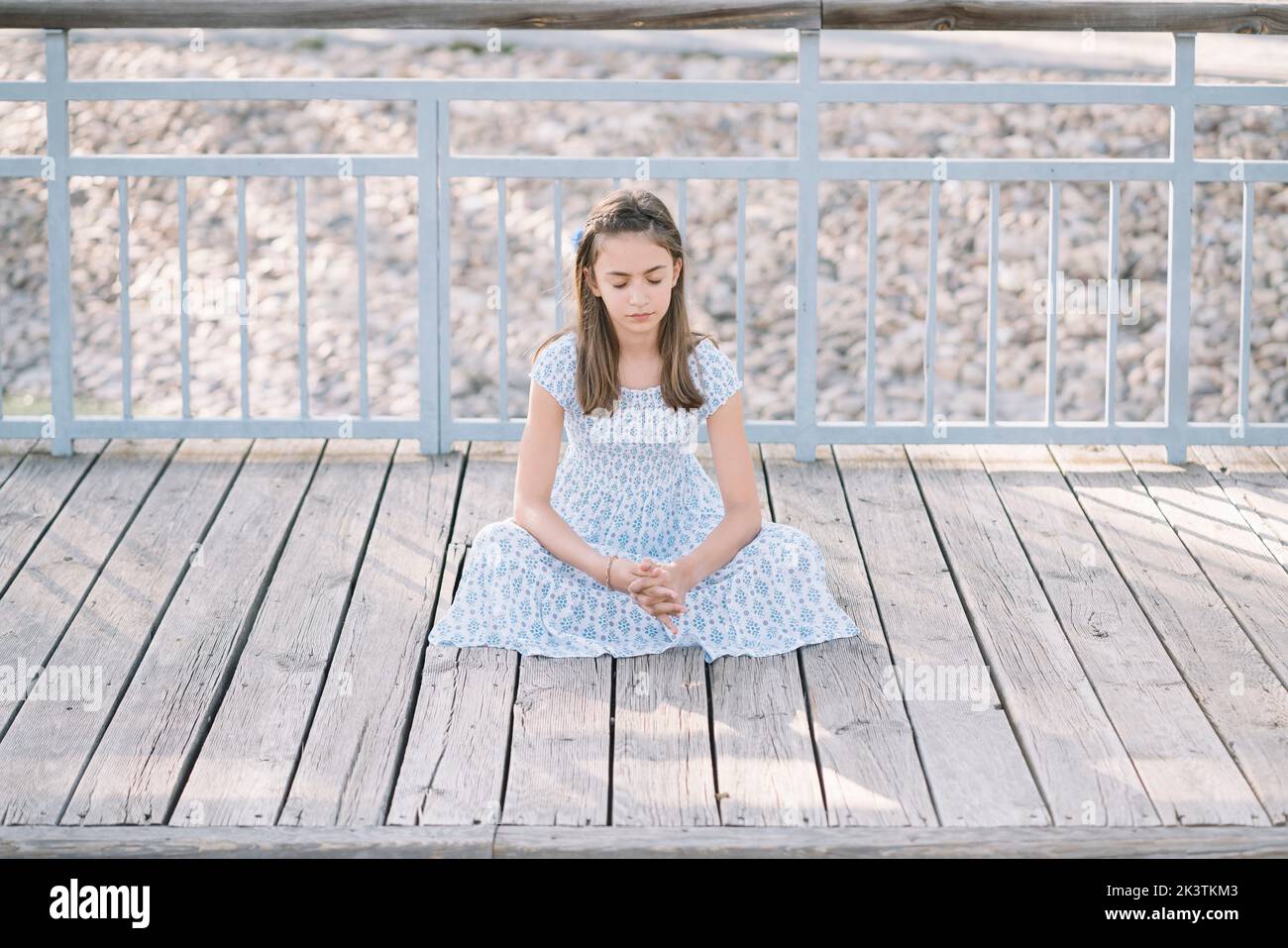 Young girl sitting on bridge Stock Photo - Alamy