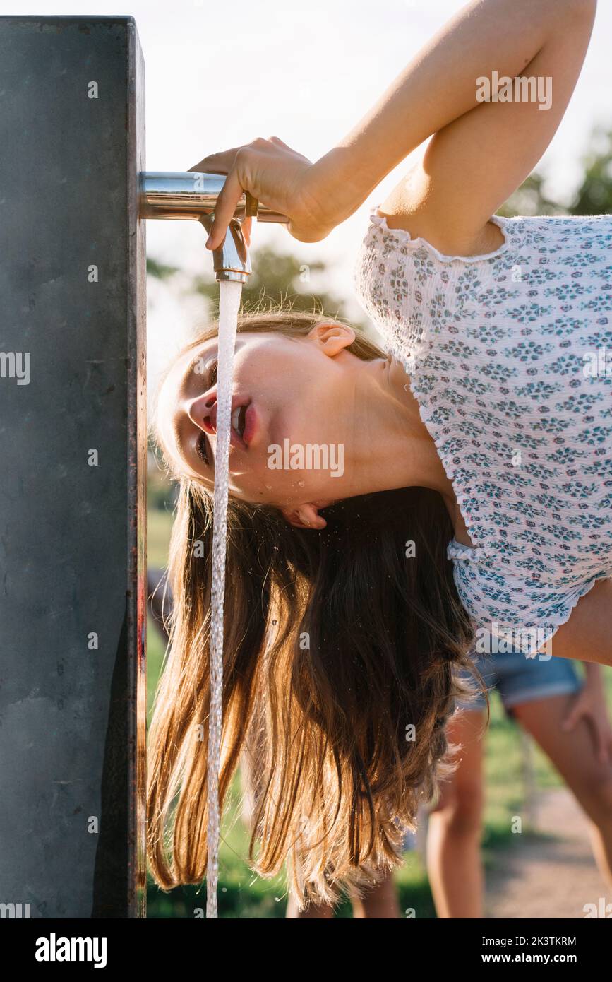 Girl drinking water from standpipe Stock Photo - Alamy