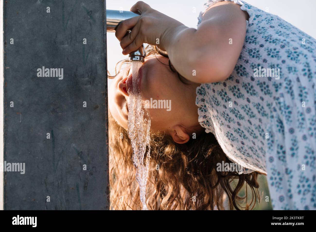 Girl drinking water from standpipe Stock Photo - Alamy