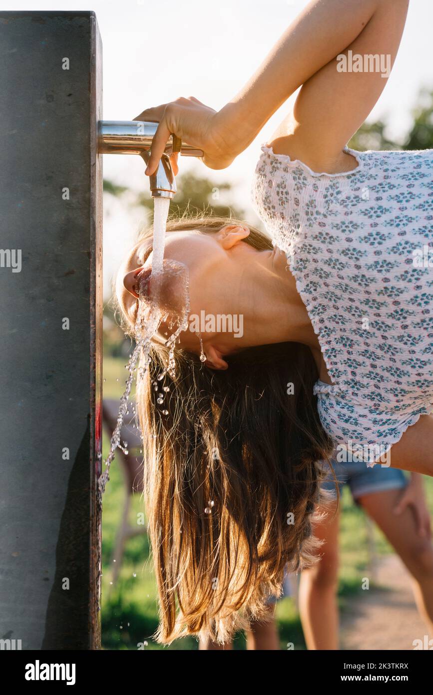 Girl drinking water from standpipe Stock Photo - Alamy