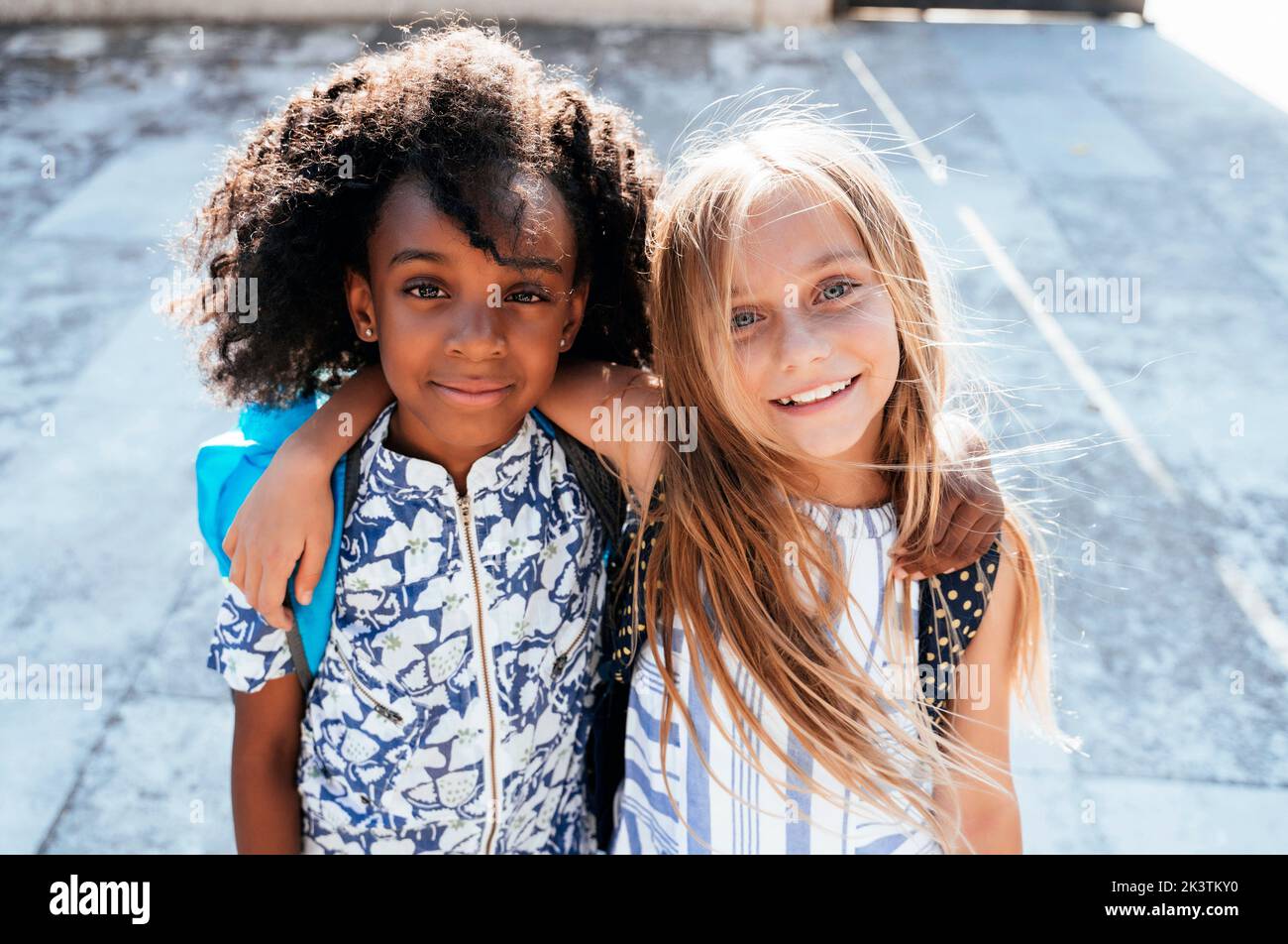 Laughing African American girl embracing friend standing on street in ...
