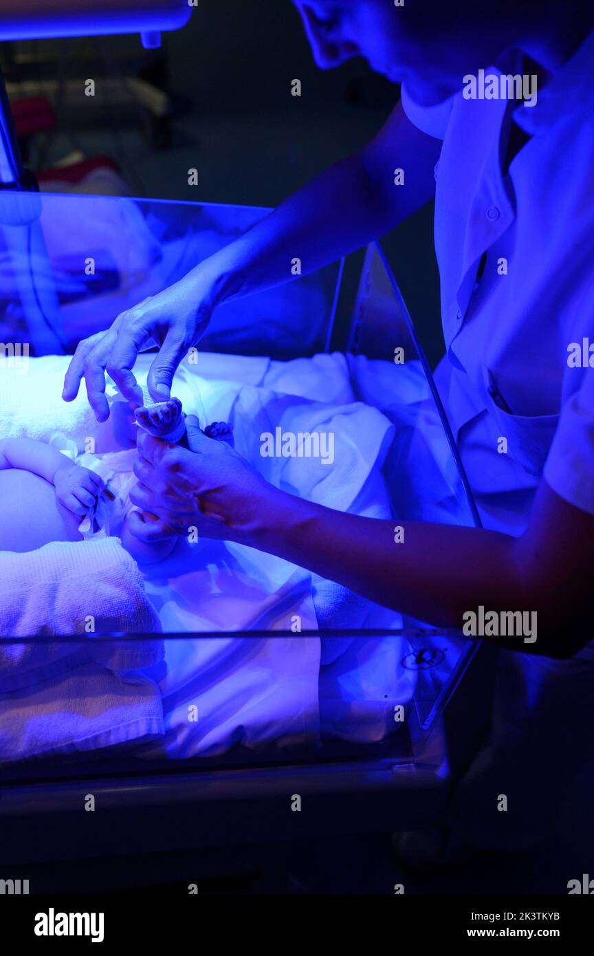 From above crop person holding small foot of sick tiny baby lying in ...