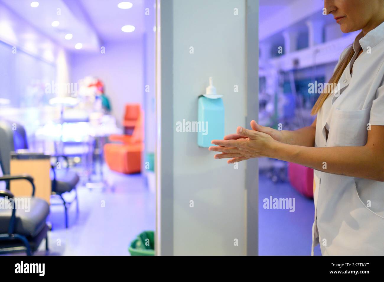 Side view of crop woman in white medical scrubs cleaning and rubbing ...