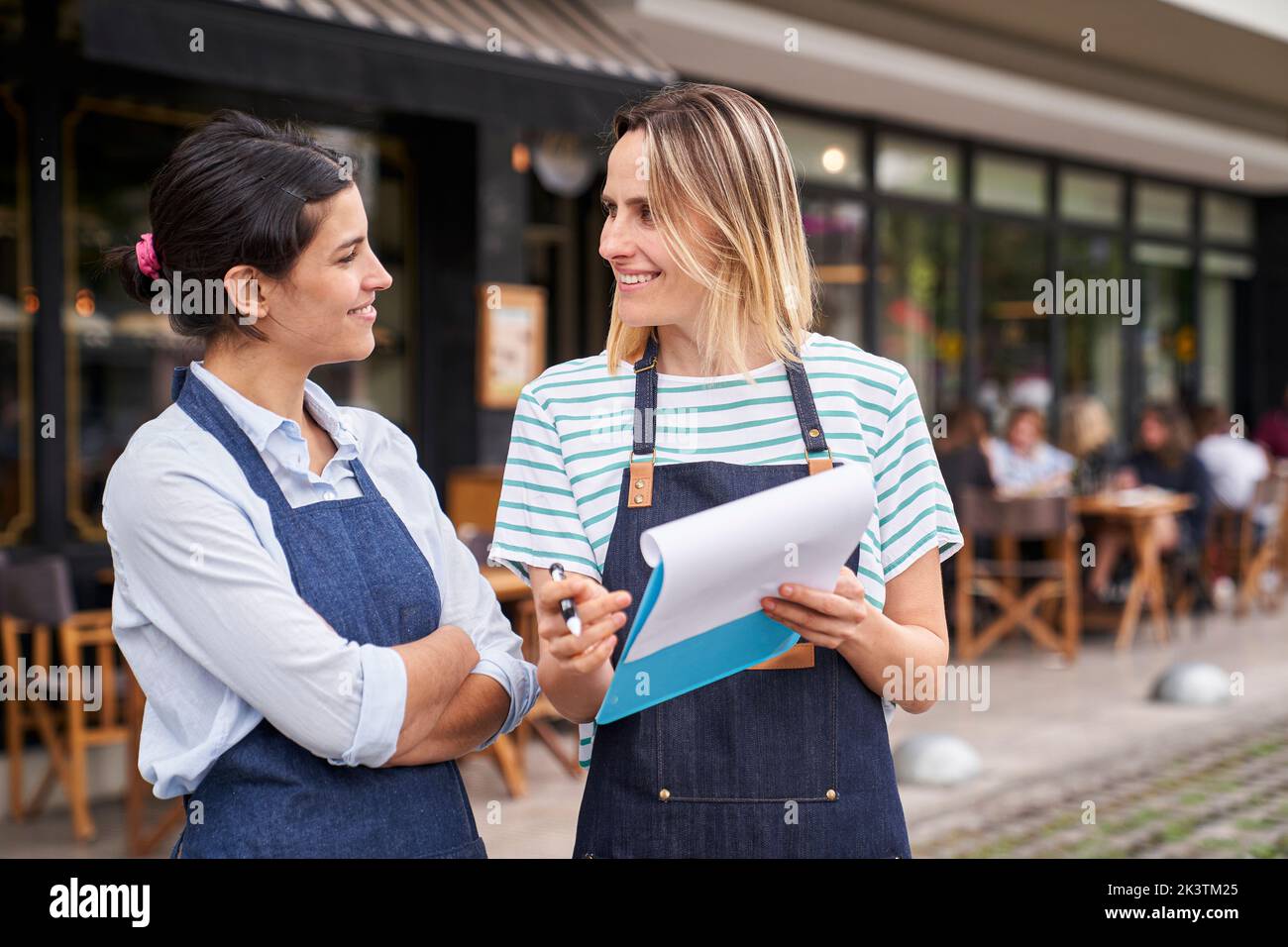 Mid-shot of two female restaurant owners checking a list outside their ...