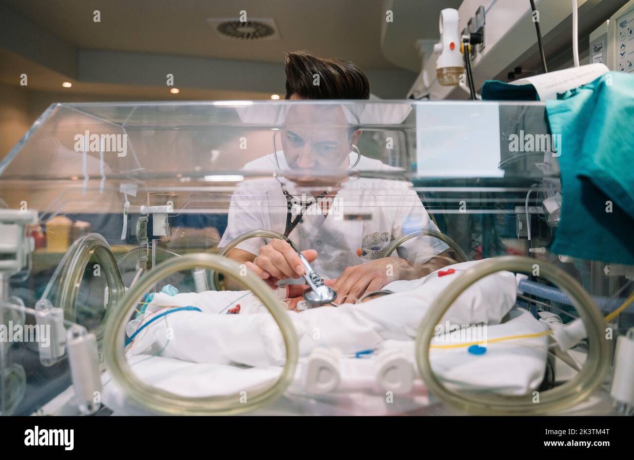 Doctor male attentively listening with stethoscope to faceless newborn ...