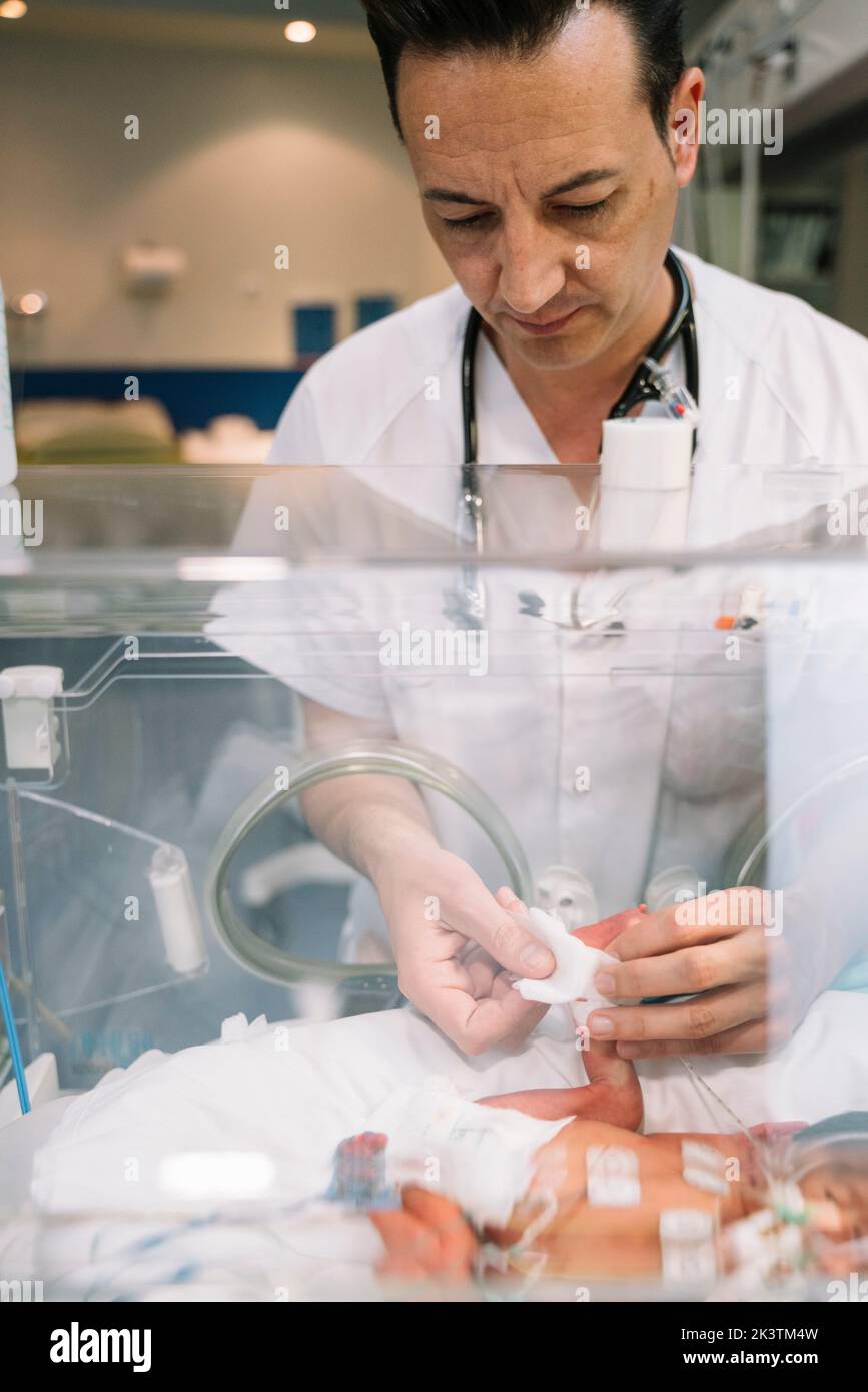 Doctor male attentively taking care of faceless newborn baby lying in ...