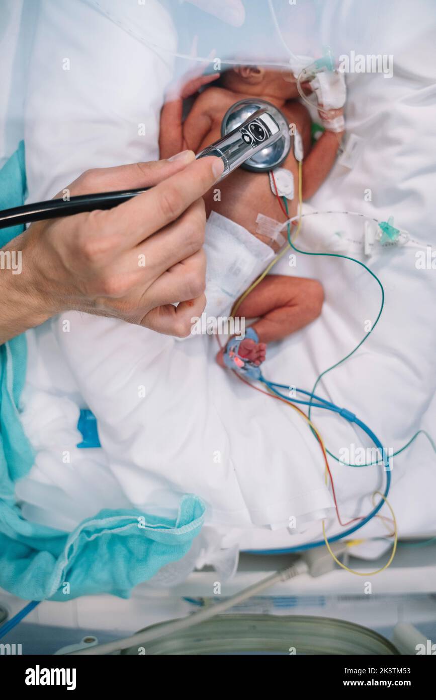 Crop doctor hand with stethoscope listening to heart anonymous newborn ...
