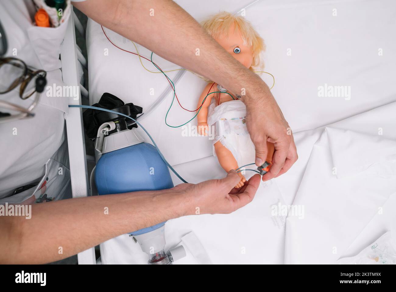From above hands unrecognizable doctor testing on doll installation of ...