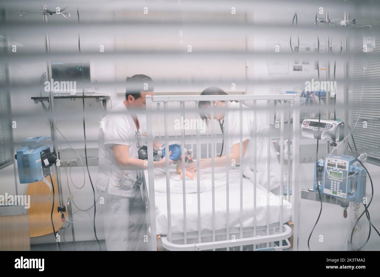 Faceless doctors standing near hospital bed with newborn in intensive ...