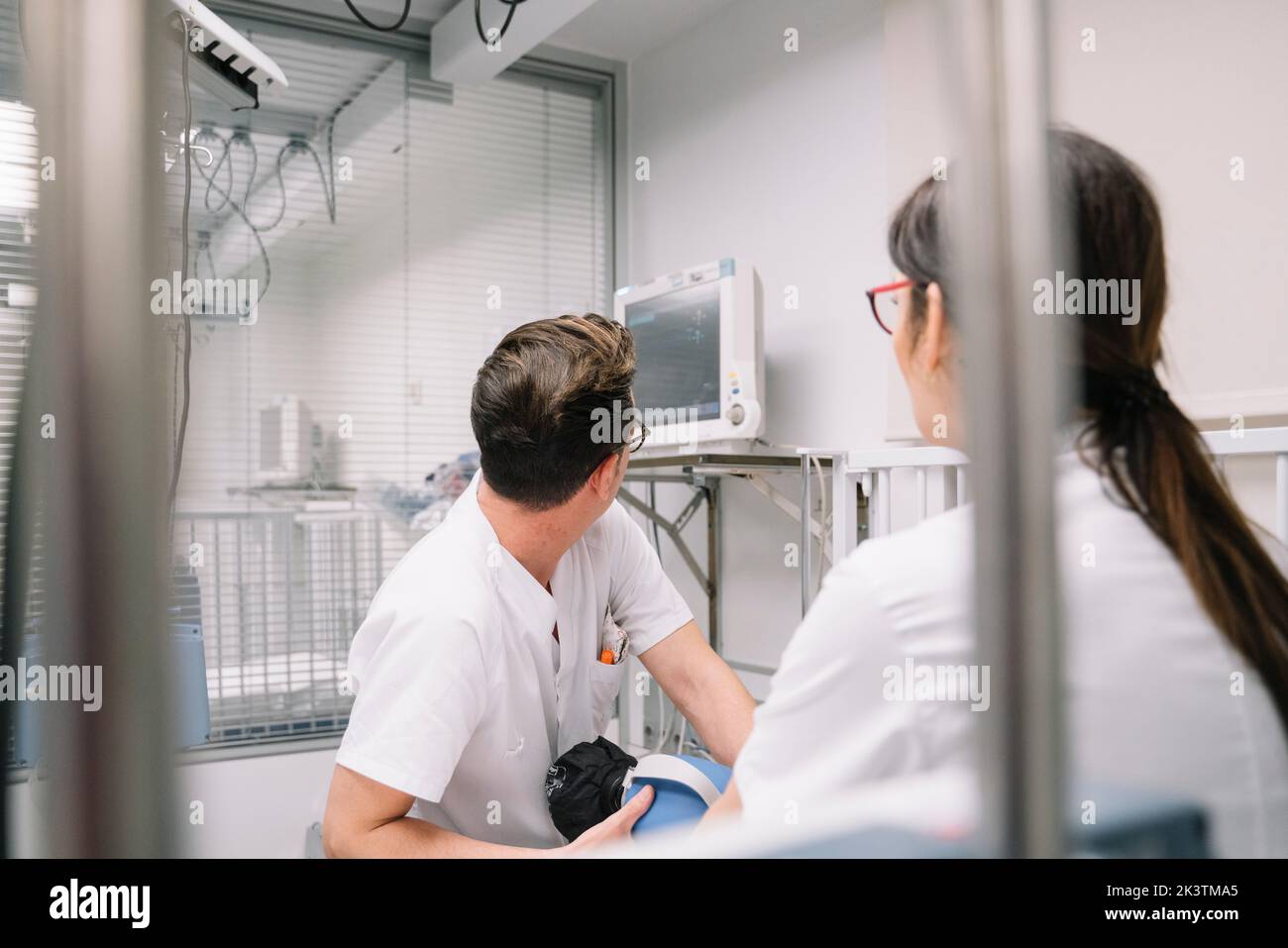 Doctors standing near hospital bed with newborn in intensive care unit ...