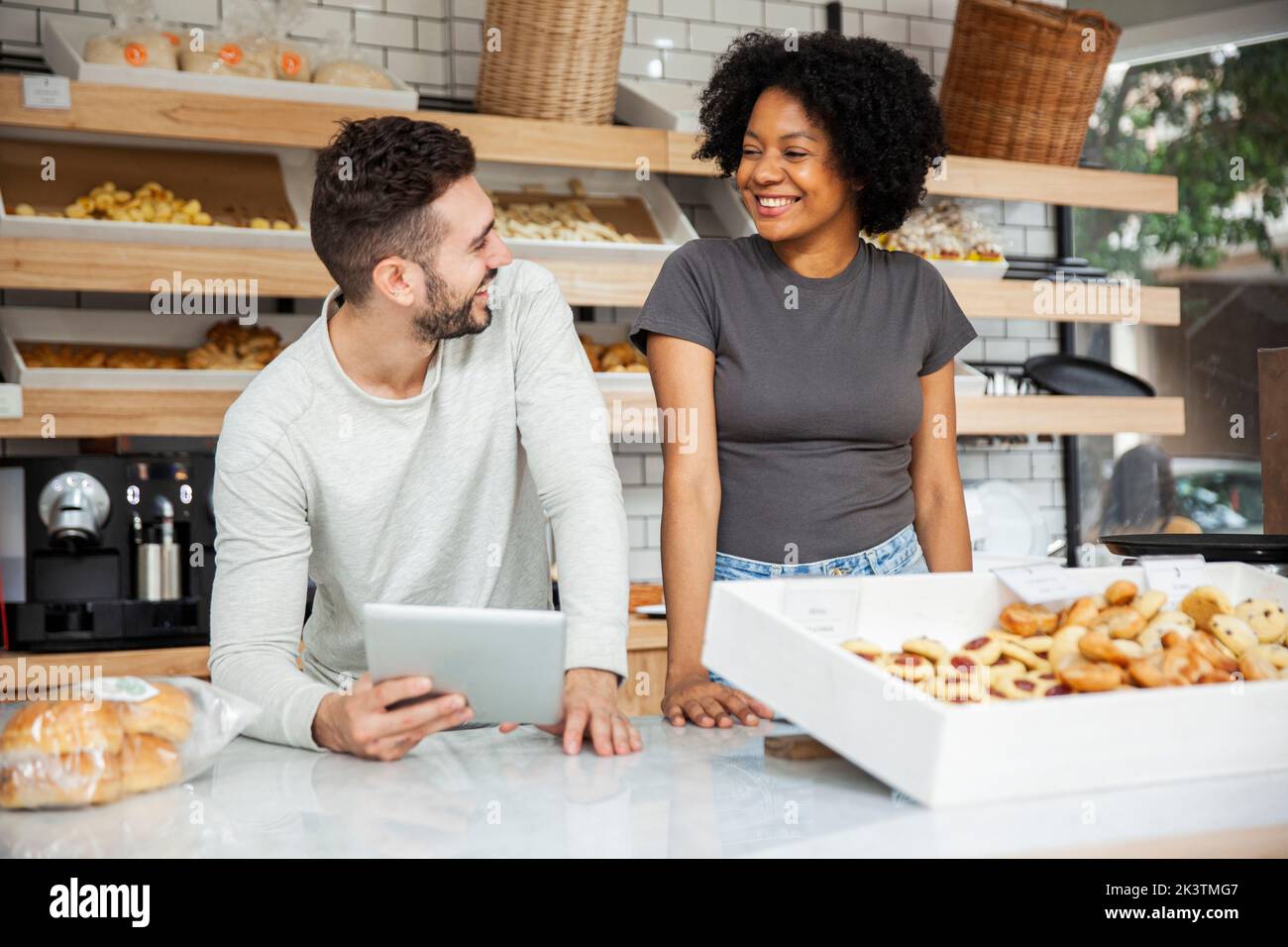 Bakery coworkers smiling at each other while standing behind counter ...