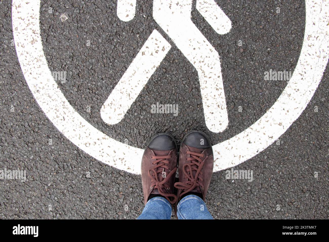 The pedestrian sign is drawn on the pavement and next to it are female ...