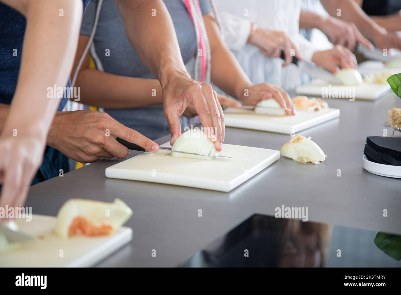 Crop man using knife for cutting onion while standing by table with ...