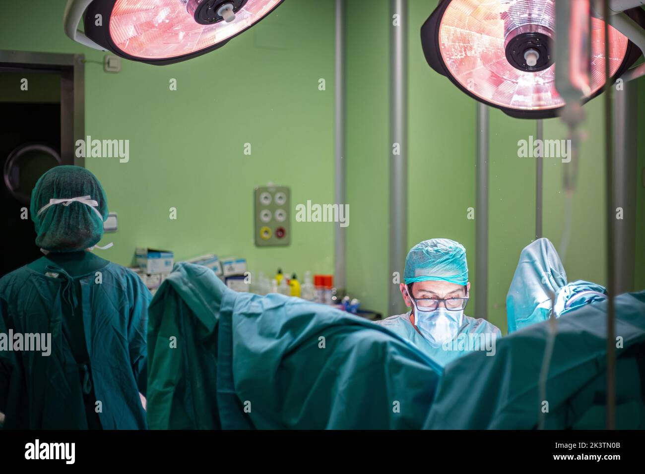 Male doctor in glasses and uniform performing surgery on patient with ...