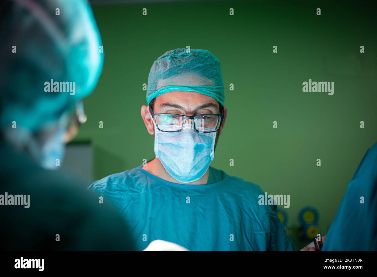 Male doctor in glasses and uniform performing surgery on patient with ...