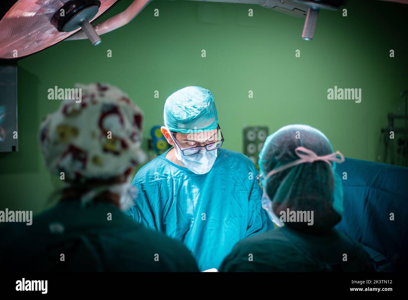 Male doctor in glasses and uniform performing surgery on patient with ...