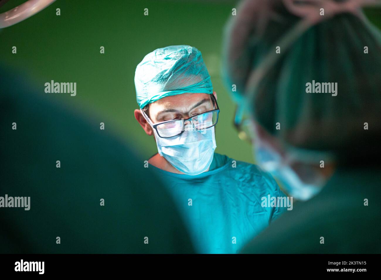 Male doctor in glasses and uniform performing surgery on patient with ...