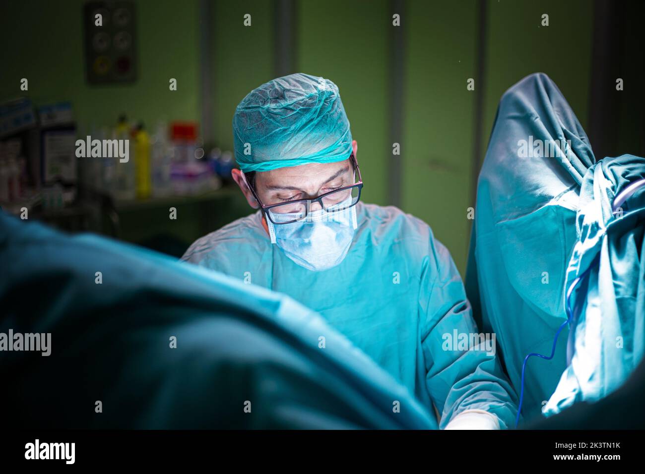 Male doctor in glasses and uniform performing surgery on patient with ...