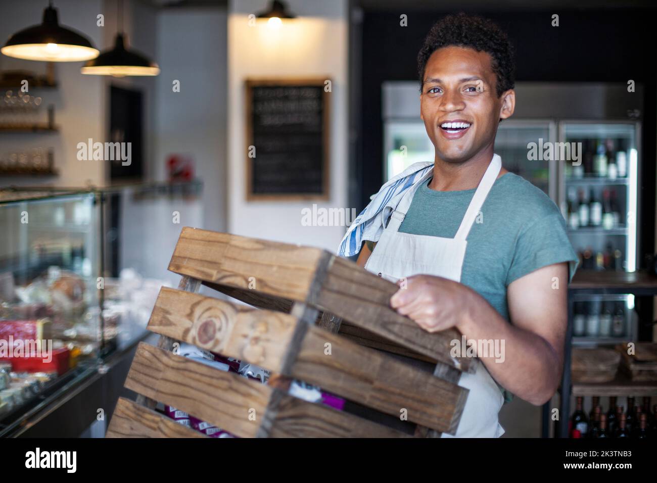 Young Latin American grocery store worker carrying wooden crate Stock ...