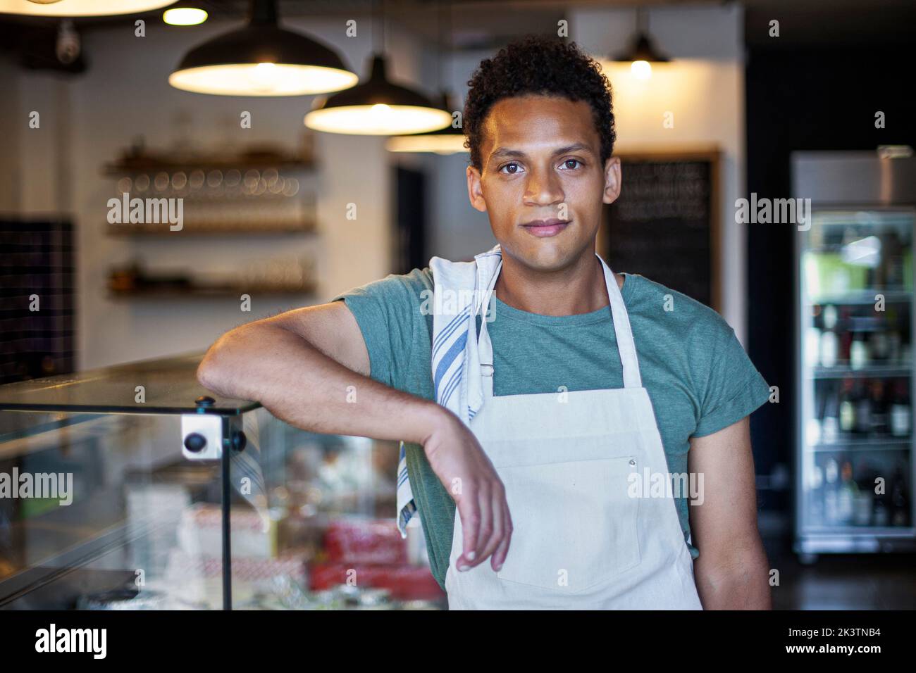 Young Latin American grocery store worker leaning on counter Stock ...
