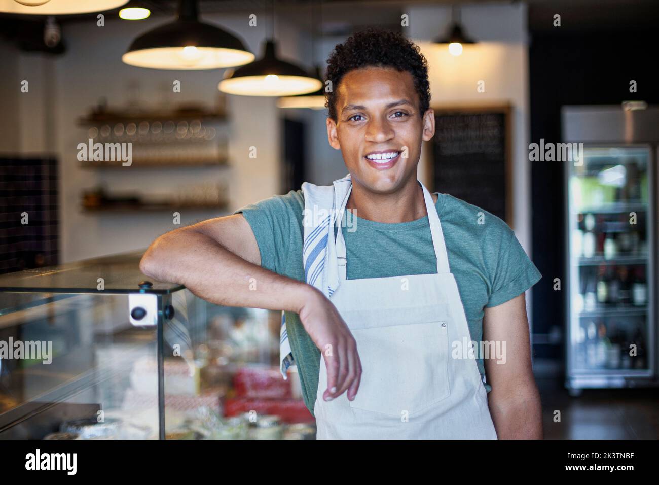 Latin American grocery store worker leaning on counter Stock Photo - Alamy