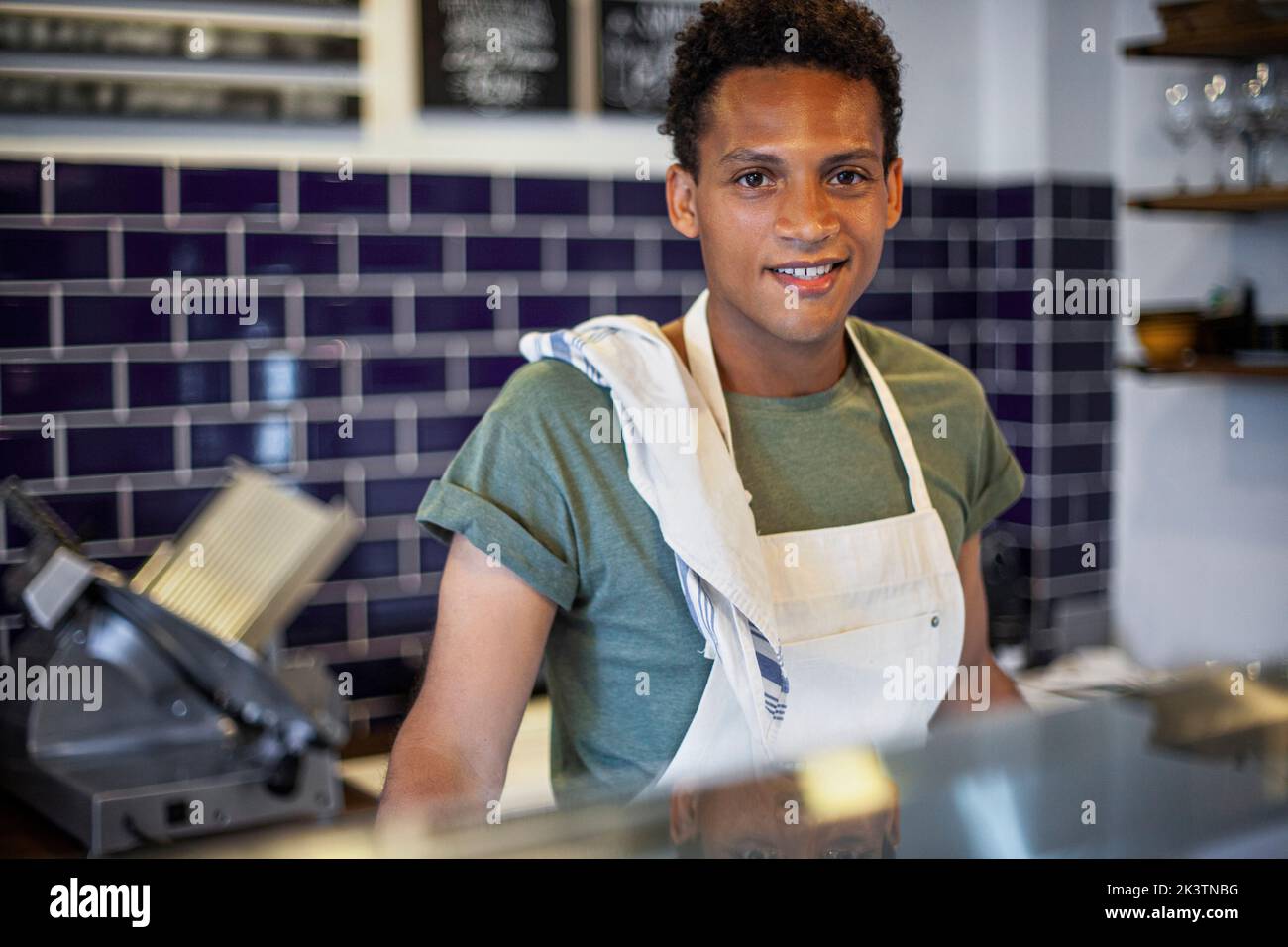Smiling Latin American grocery store worker standing behind counter ...