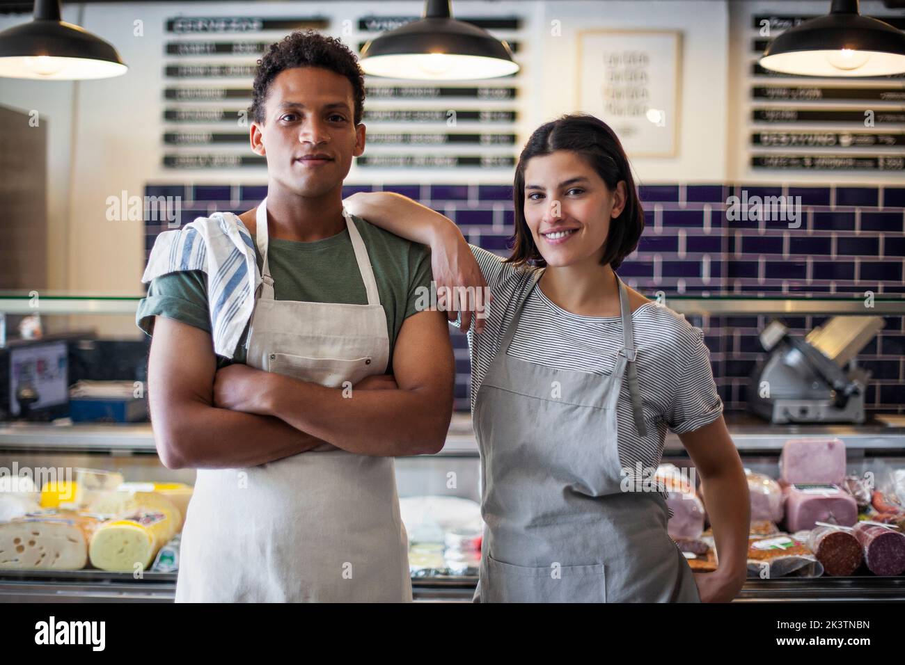 Confident grocery store owners looking at the camera while standing ...