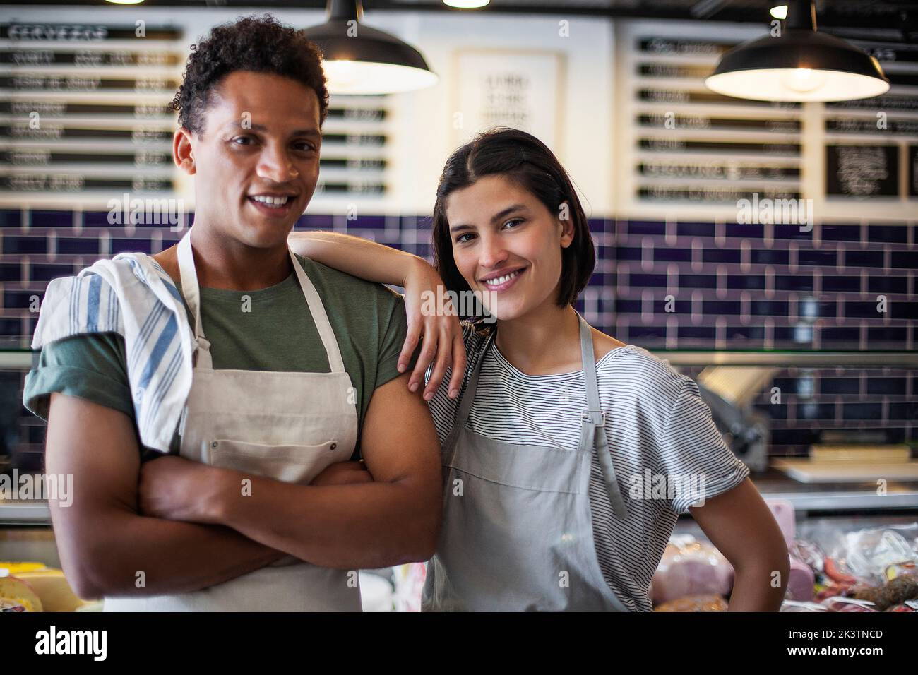 Female grocery worker leaning on coworkers shoulder while looking at ...