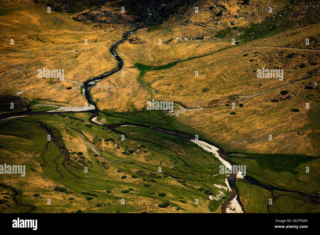 From above of narrow curvy stream running through rough rocky mountain ...