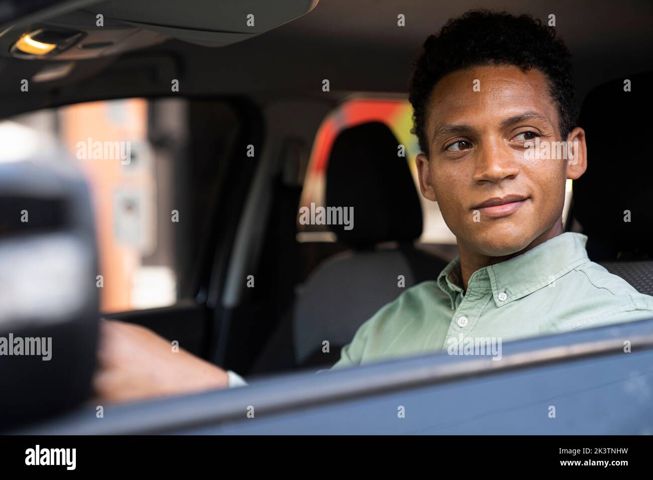 Mid-shot of handsome African-American businessman inhis car behind the ...